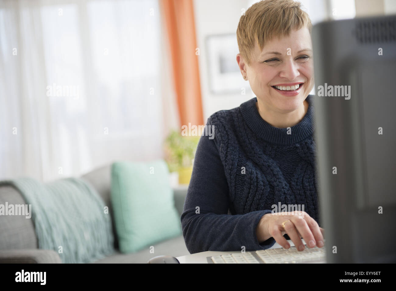 Laughing Caucasian woman using computer Stock Photo - Alamy