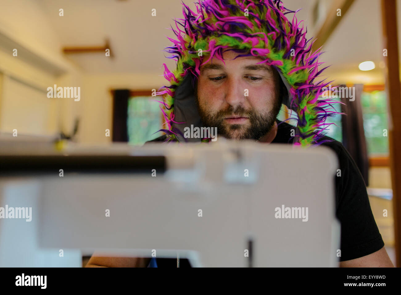 Caucasian man wearing fuzzy hat using sewing machine Stock Photo - Alamy