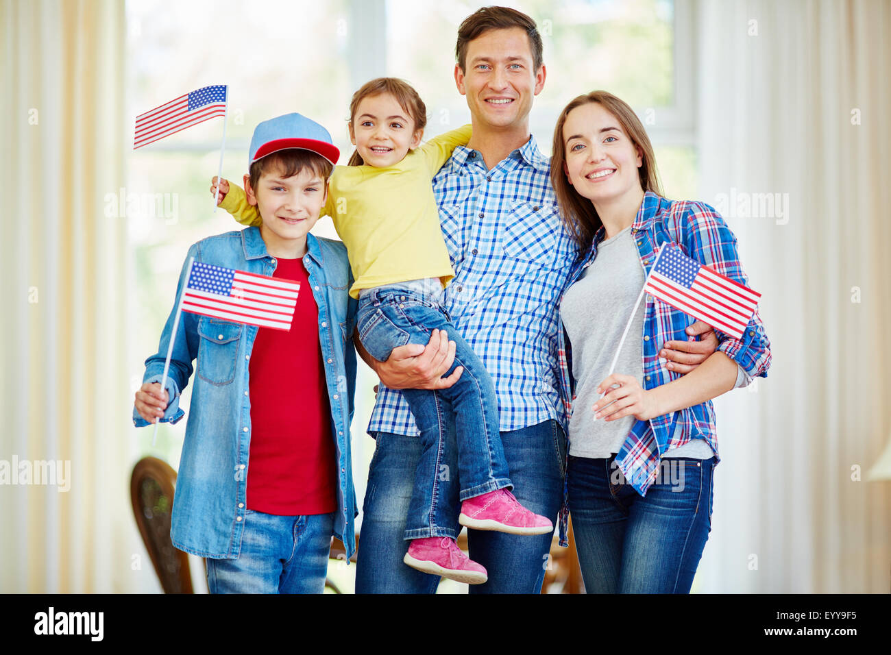 Modern American family of four holding flags Stock Photo - Alamy