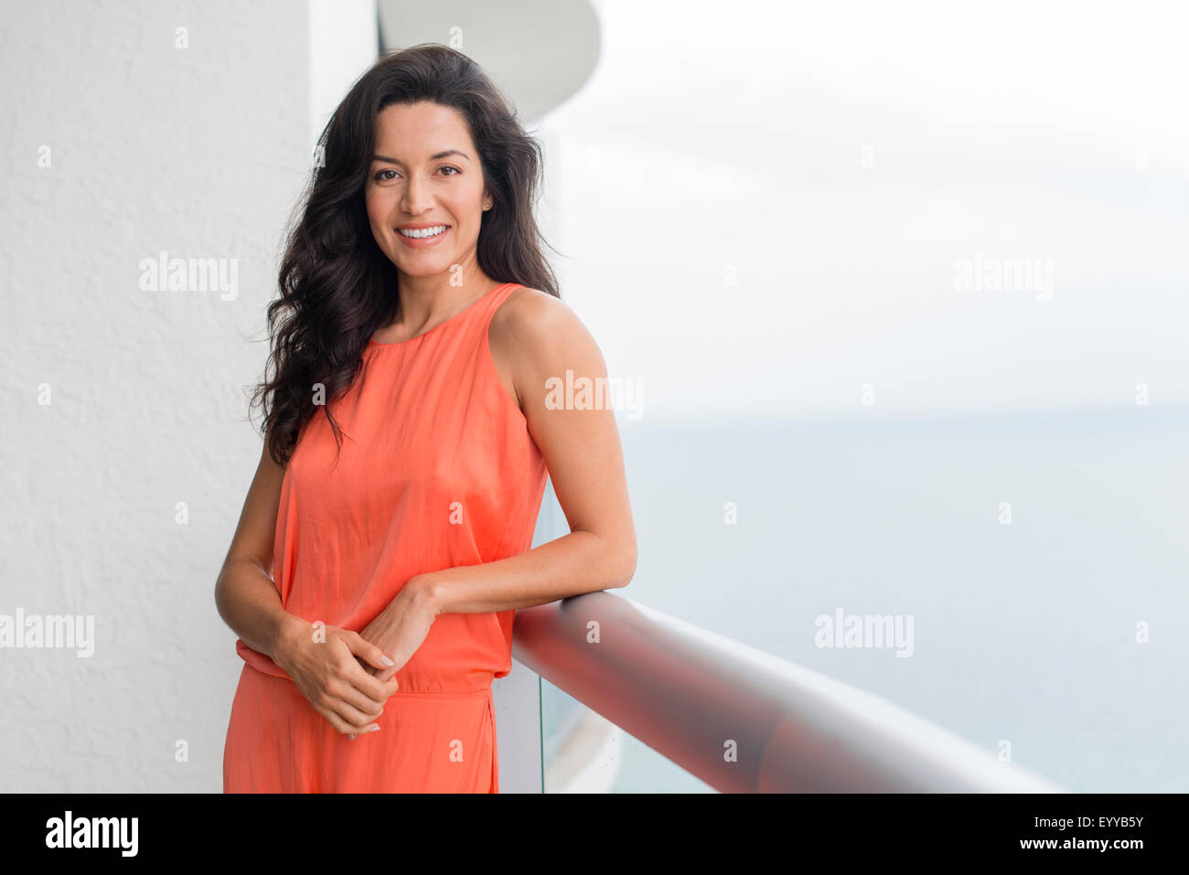 Hispanic woman leaning on balcony Stock Photo - Alamy