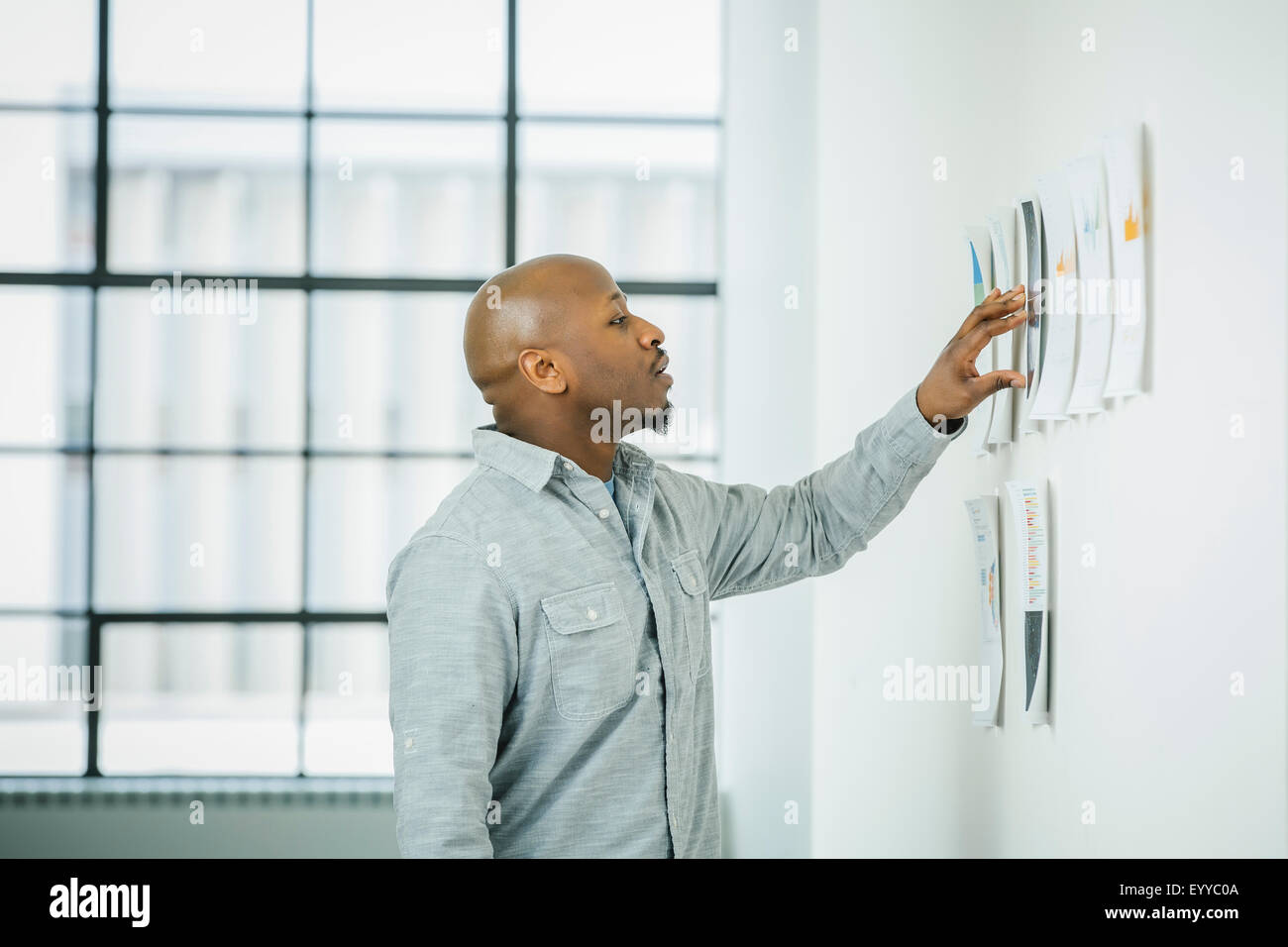Black businessman examining paperwork on office wall Stock Photo - Alamy