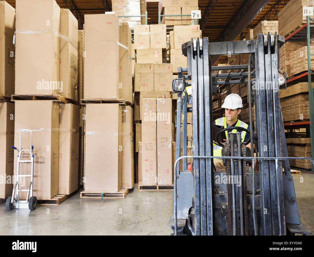 Caucasian worker driving forklift in warehouse Stock Photo - Alamy