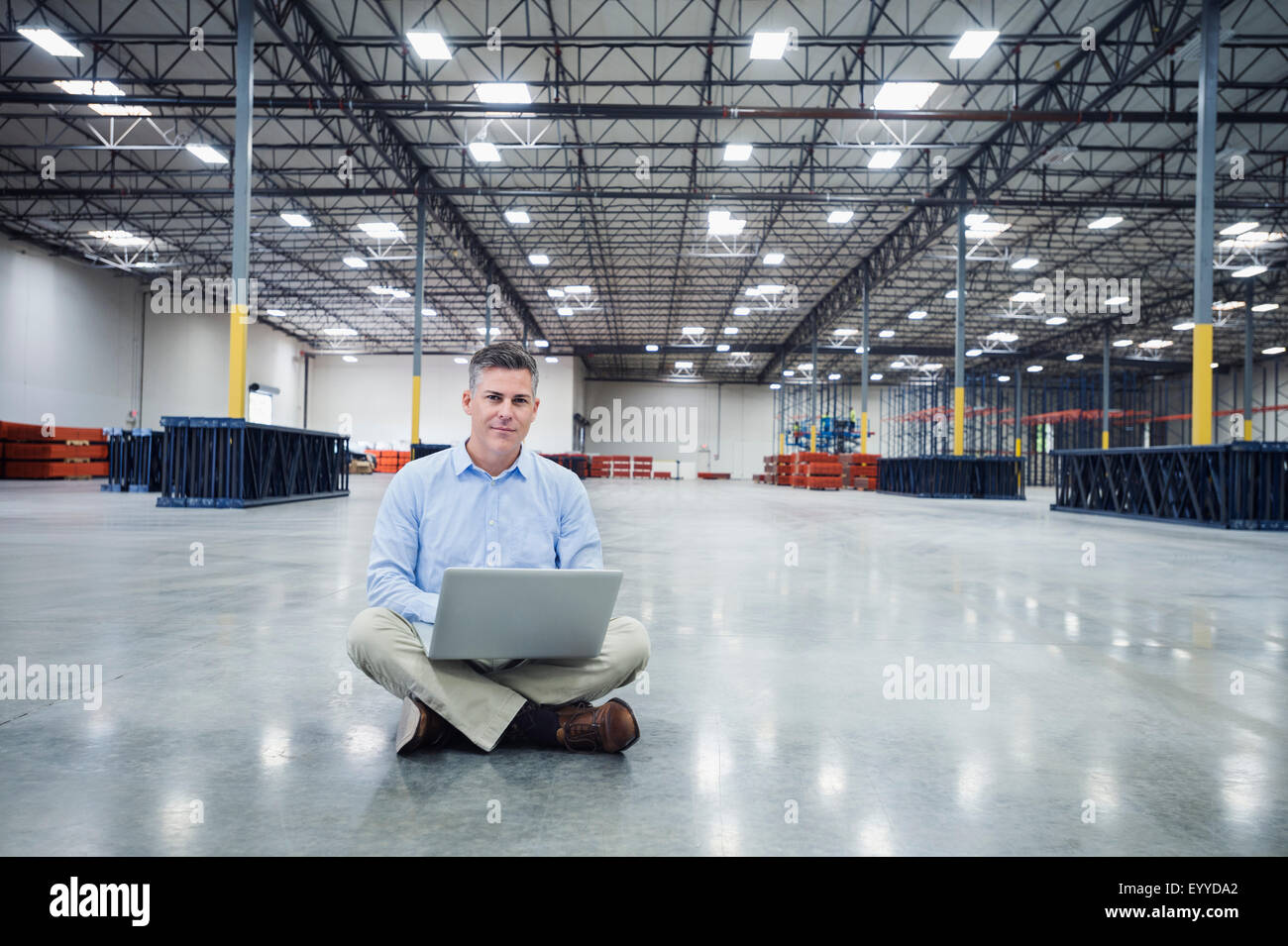 Caucasian businessman using laptop in empty warehouse Stock Photo - Alamy