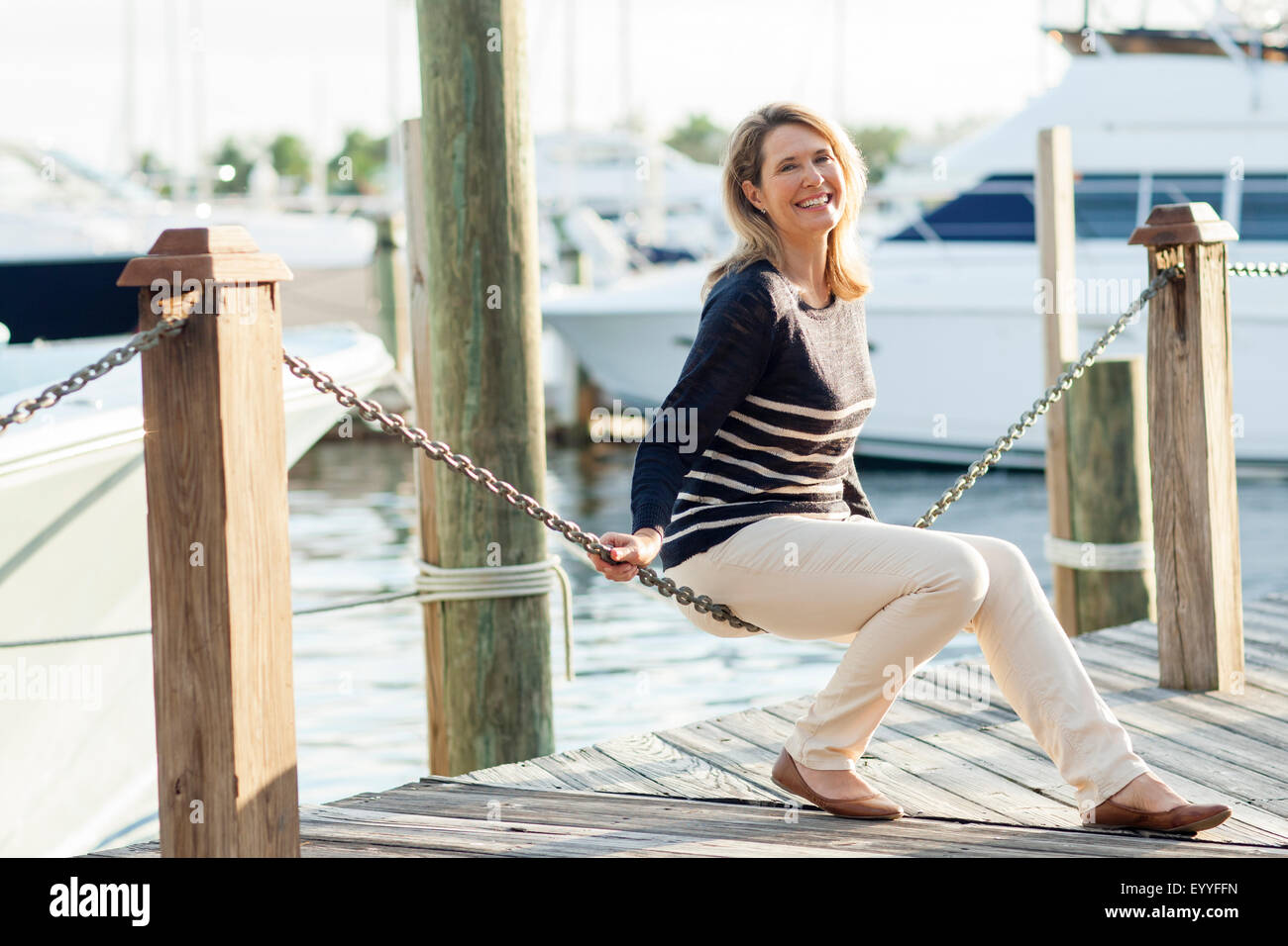 Caucasian woman sitting on dock in harbor Stock Photo - Alamy