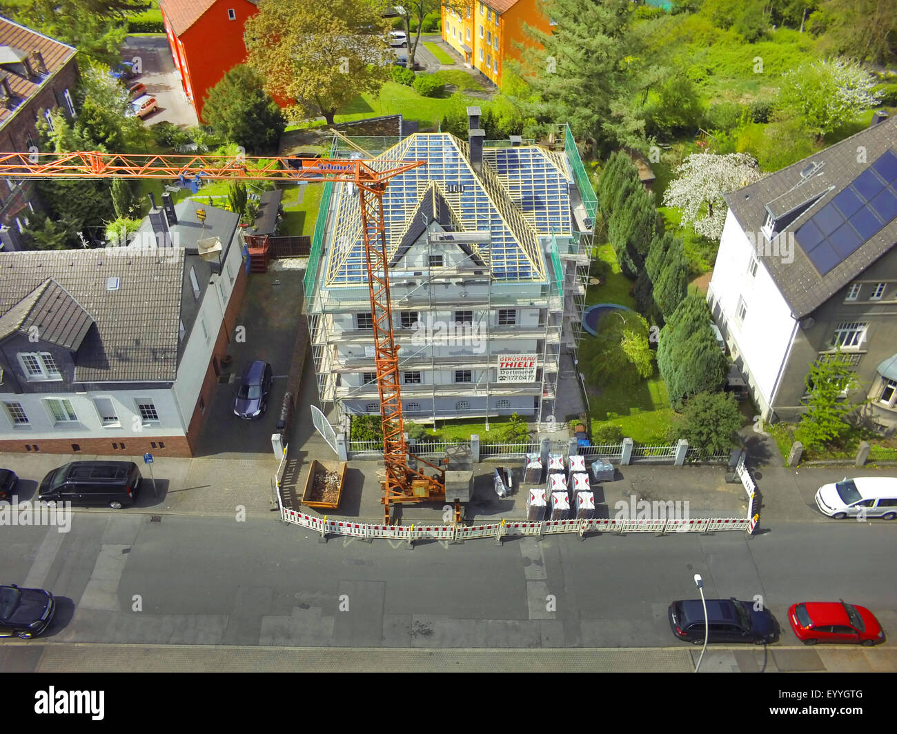 aerial view to crane and scaffolded residential building, roof is ...