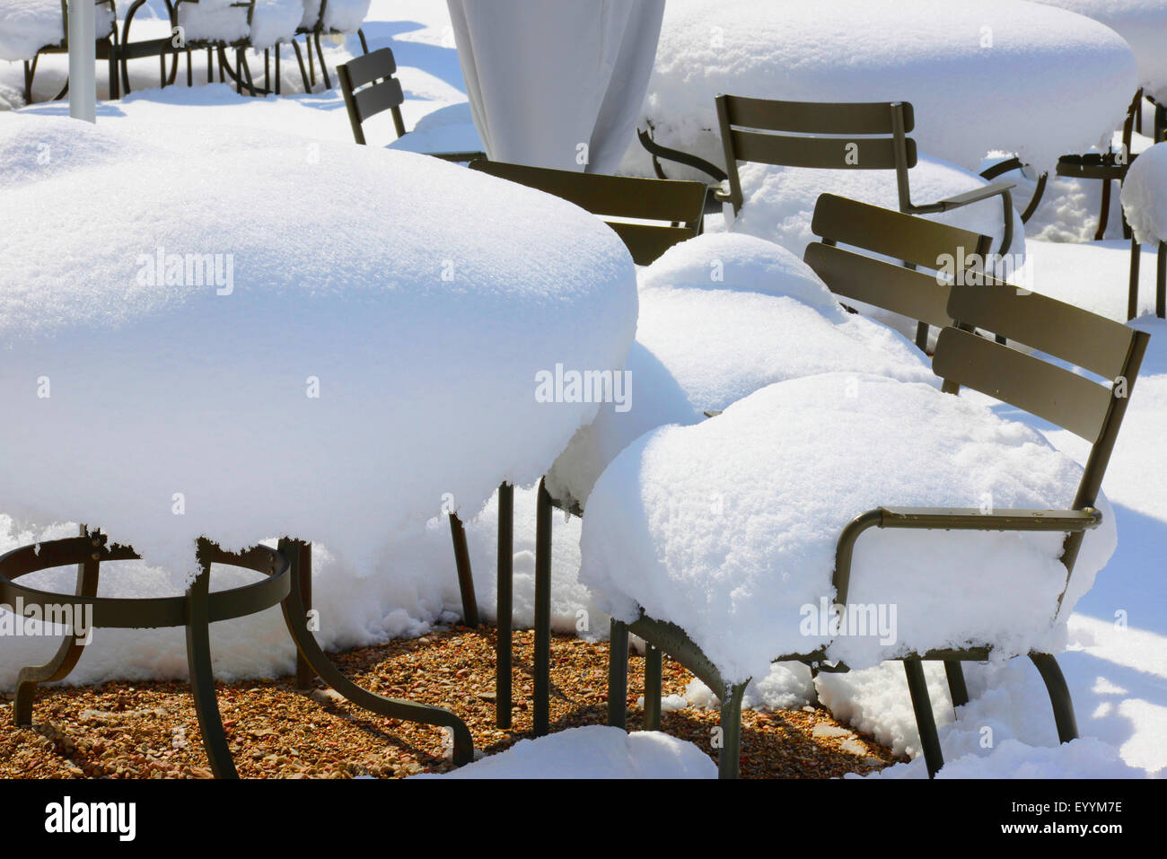 snow-covered tables and chairs of a restaurant after warm spring days, Germany, Bavaria, Swabia ...