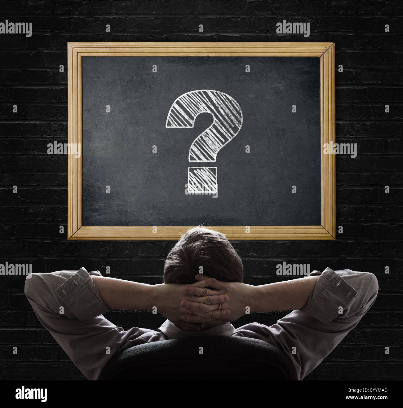 Man looking at question mark on blackboard Stock Photo - Alamy