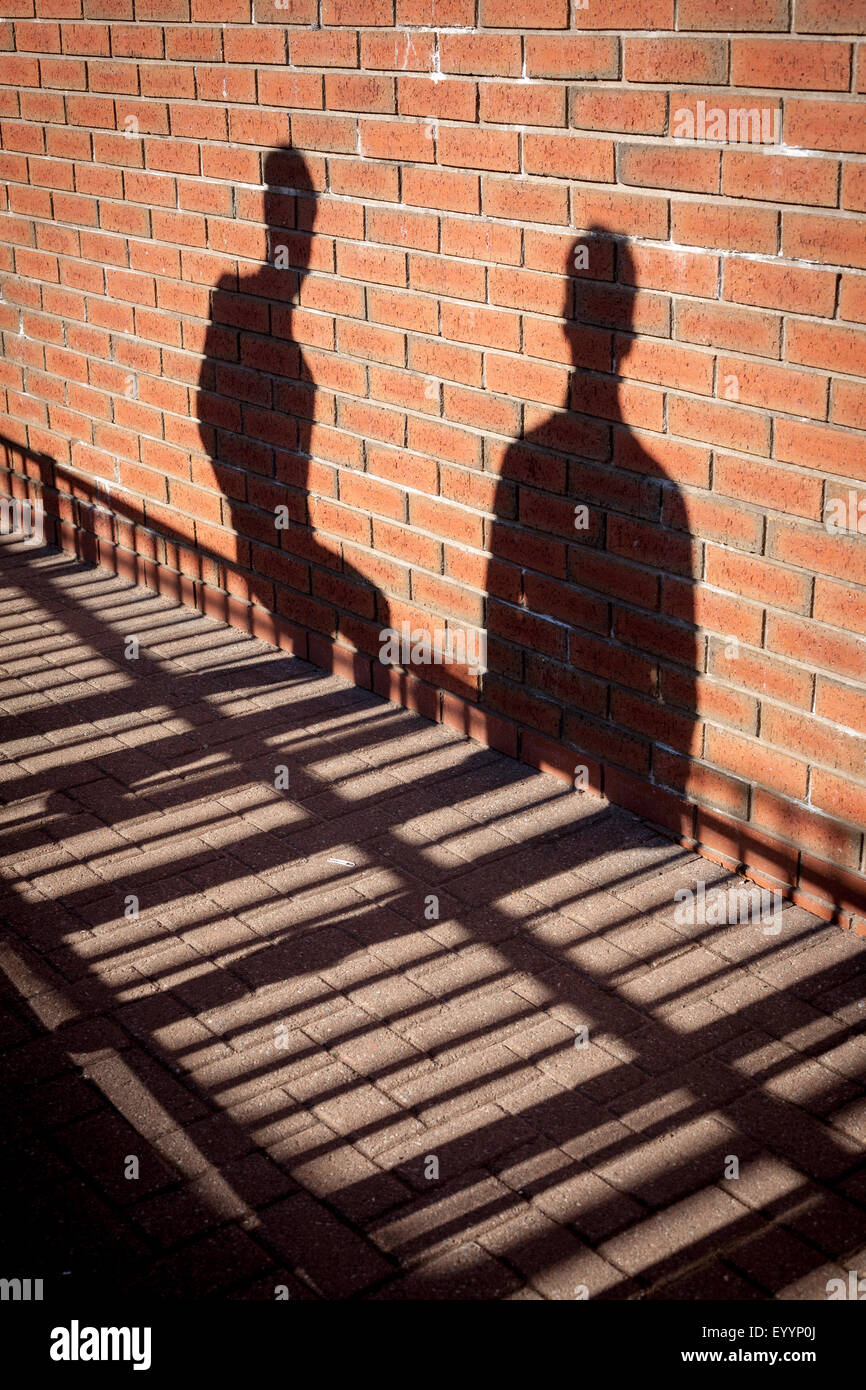 Shadows of two people sitting on fence against brick wall Stock Photo ...