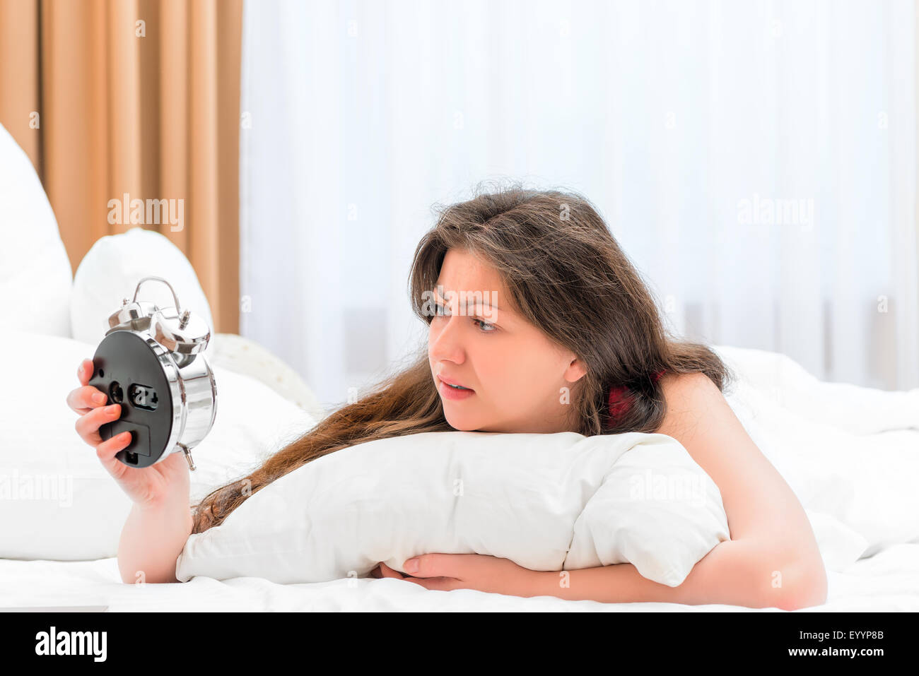 brunette girl woke up in the morning and looks at the clock Stock Photo ...