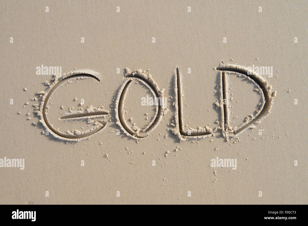 Simple gold message handwritten in clean text on smooth sand beach in ...