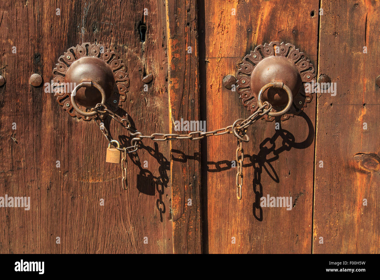 Close up front view of wooden old door, closed with chains and locked ...