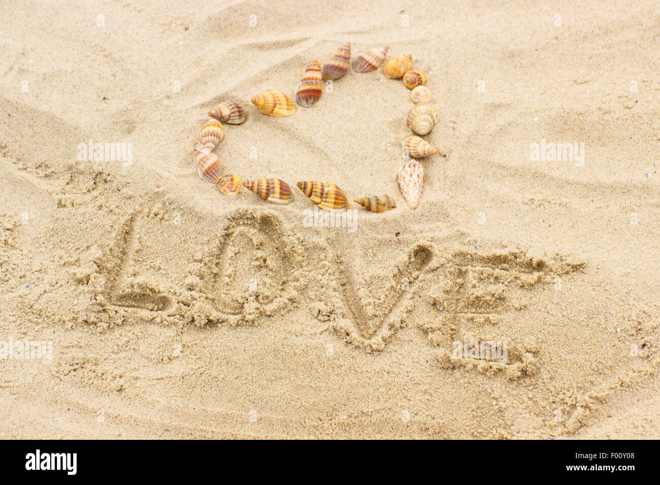 Word love written on sand at the beach and heart of shells, symbol of ...