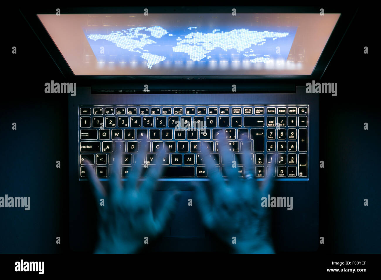 Hands are typing on a laptop computer in the dark with illuminated ...