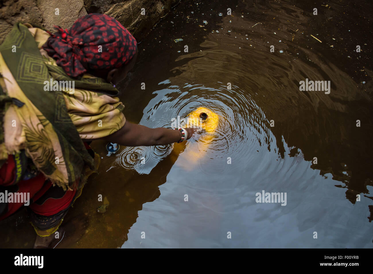 Woman takes water from a well before returning to her village. The ...