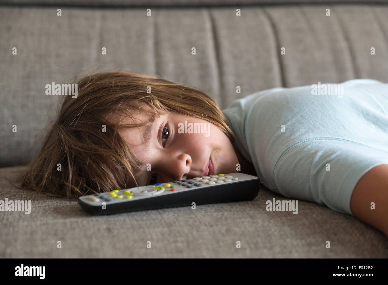 Little girl watching TV on the couch stretched Stock Photo - Alamy
