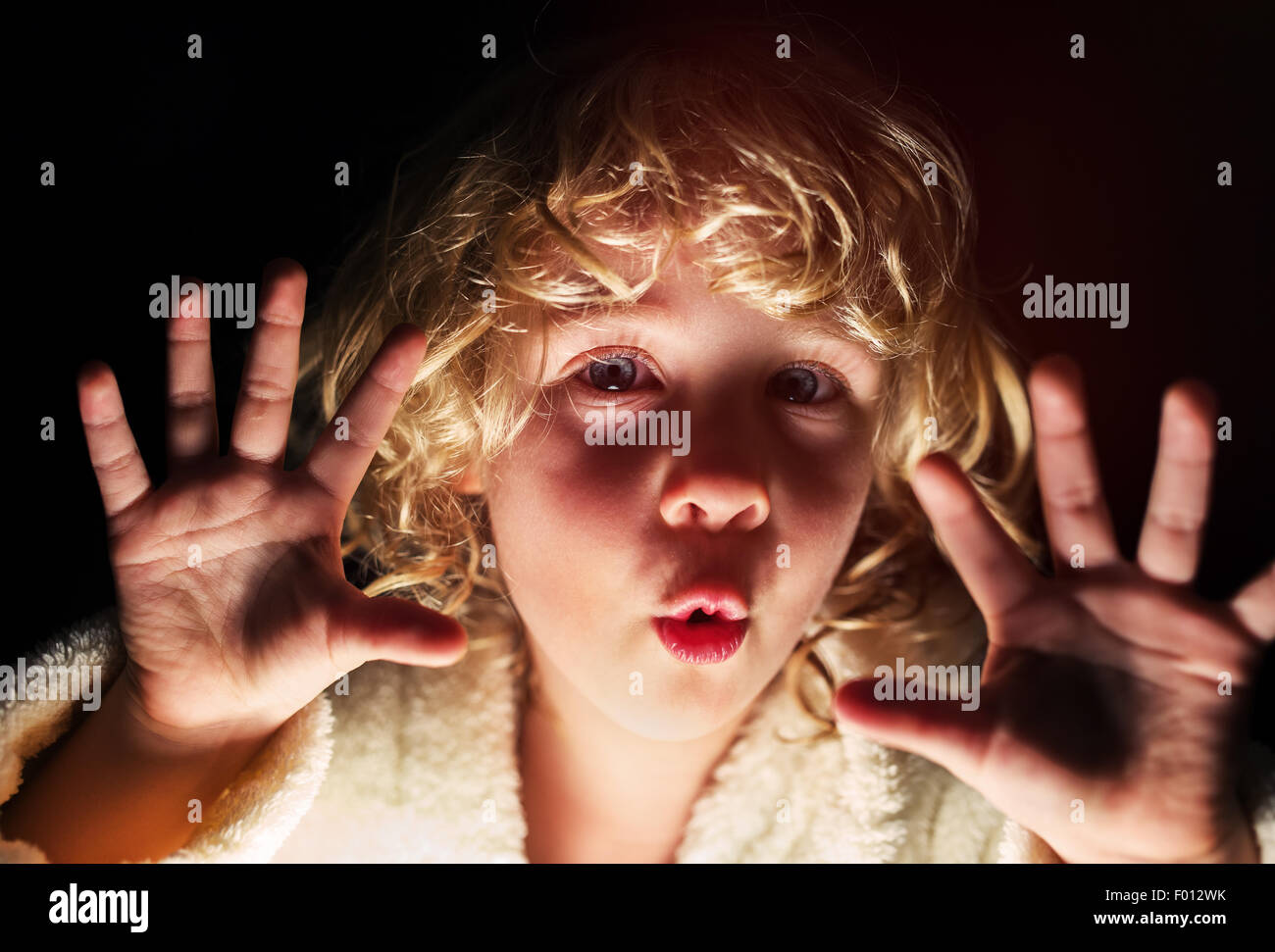 Portrait of cute girl looking at camera with frightening expression ...