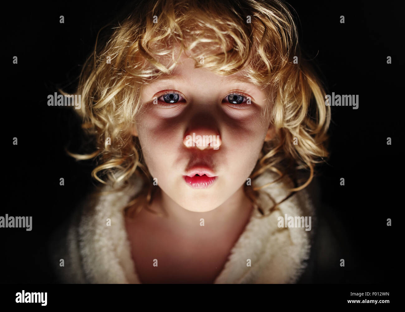 Portrait of cute girl looking at camera with frightening expression ...