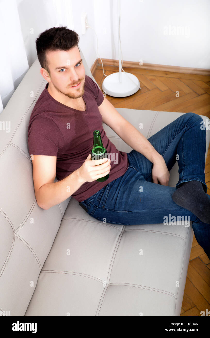 Portrait of a young man drinking beer at home Stock Photo - Alamy
