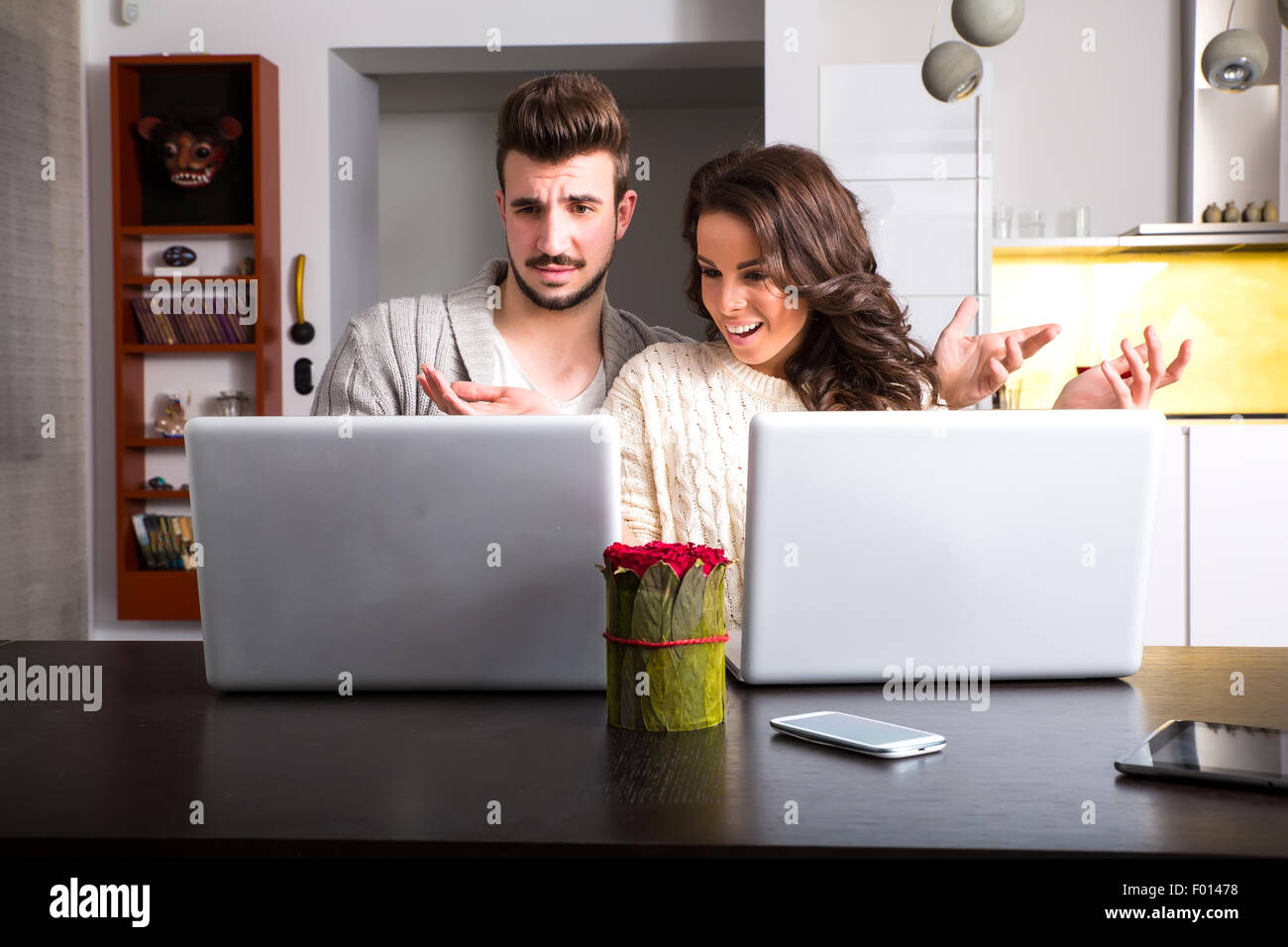 A young couple in the evening using their laptop computers at home ...