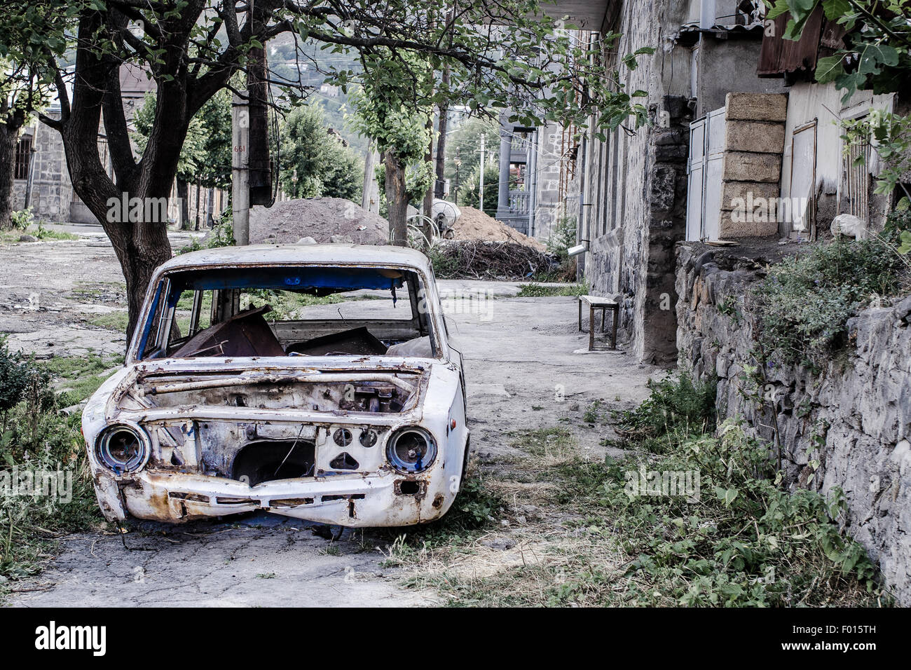 Abandoned car left to rust in a rural neighborhood surrounded by trees ...