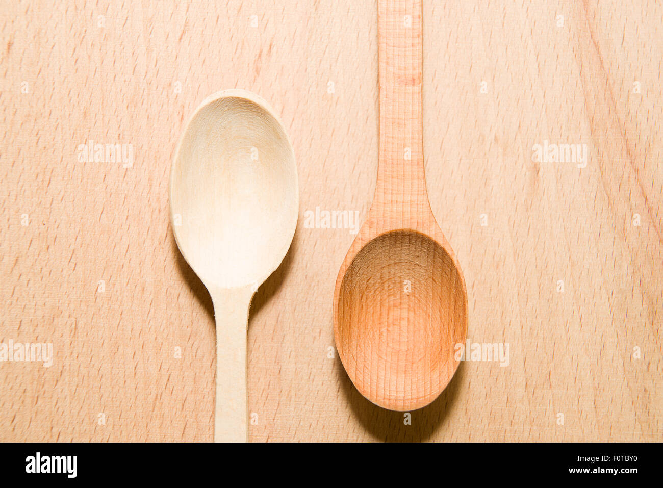 Two wooden spoons of different colors are on the surface Stock Photo ...