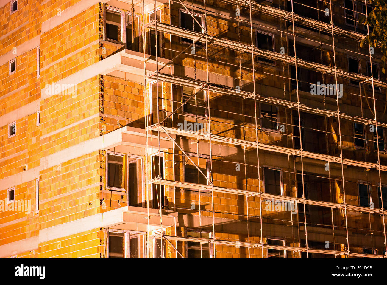 Residential building under construction at night illuminated by yellow ...