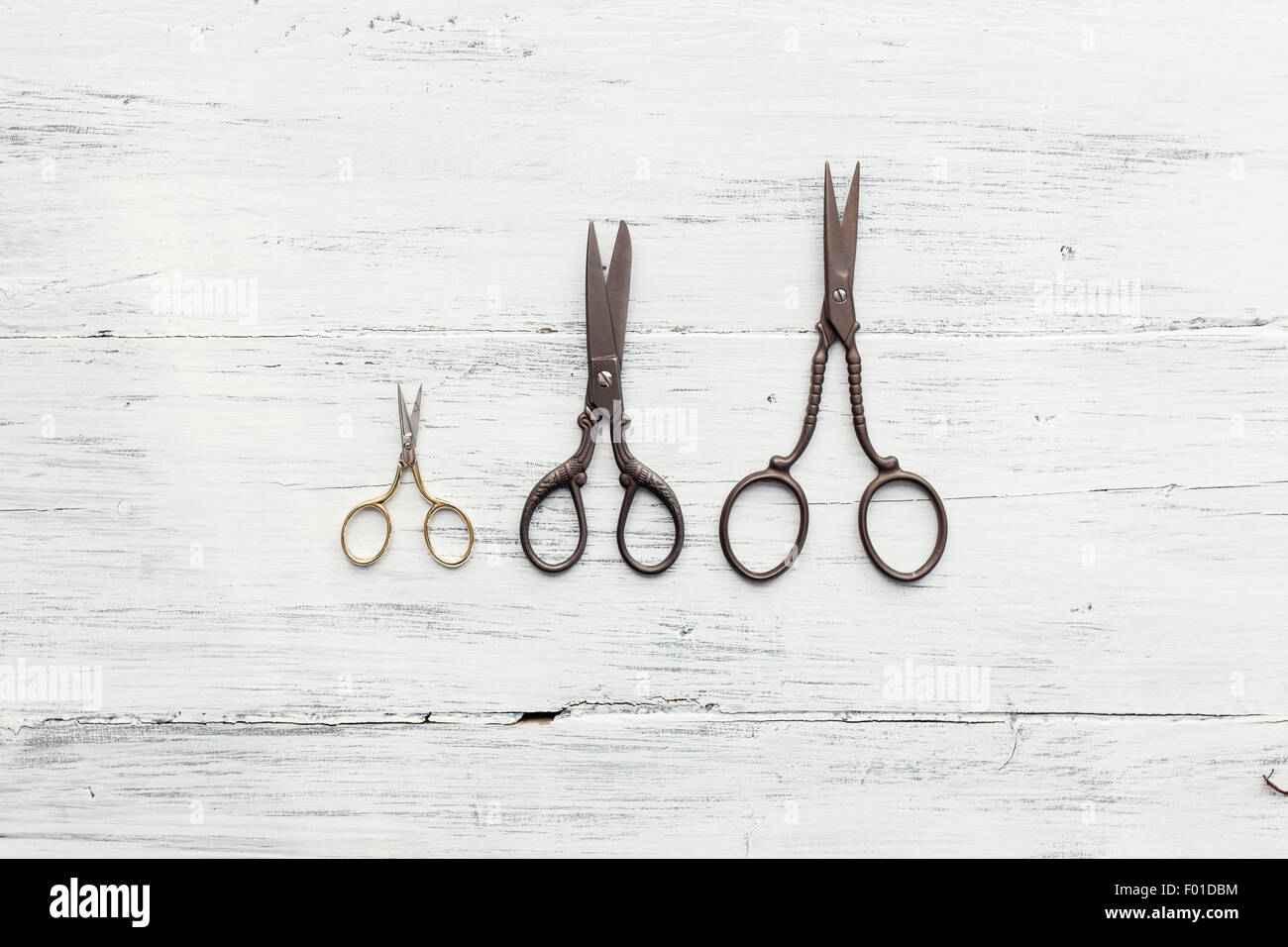 Three scissors on white wooden table Stock Photo - Alamy