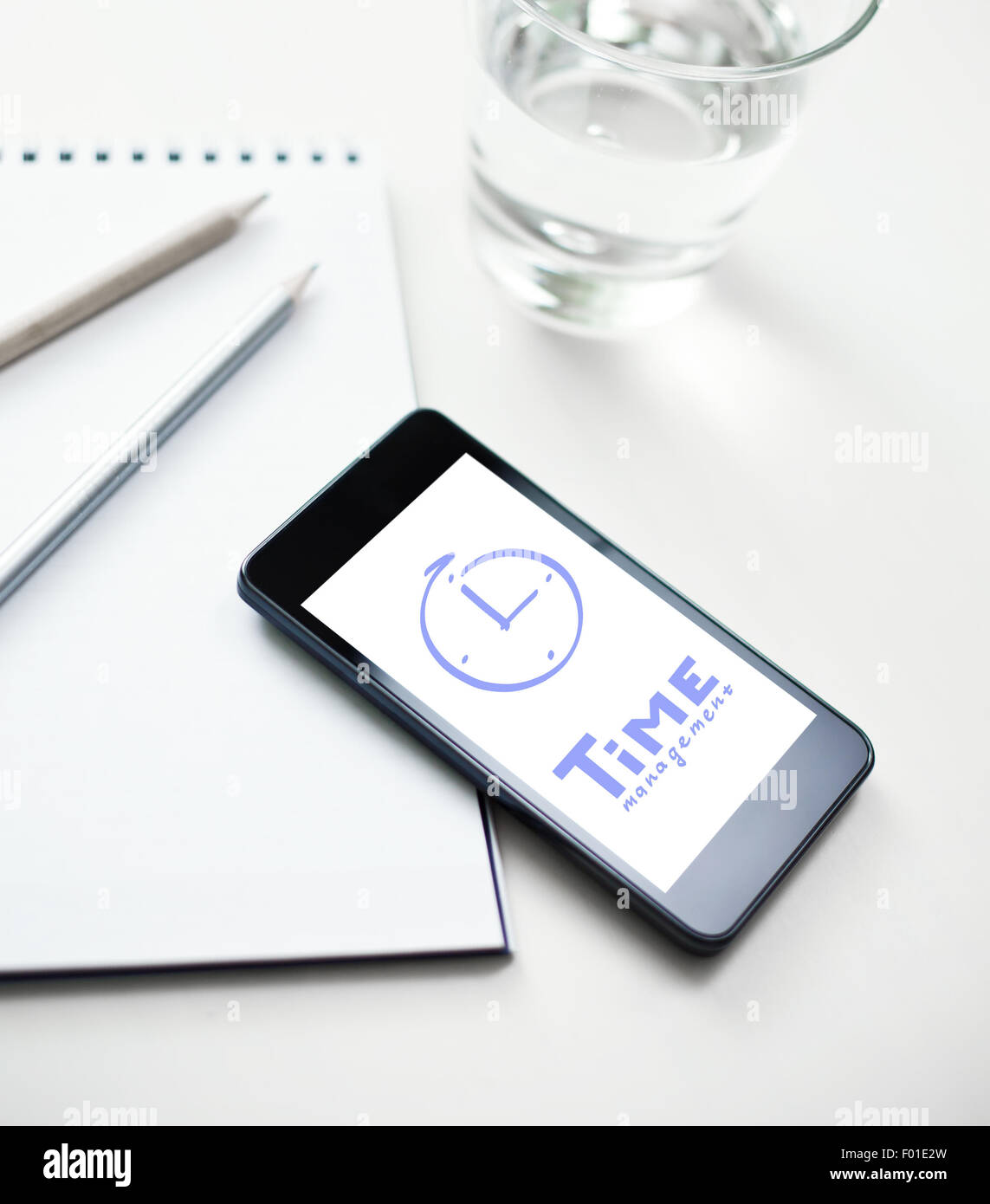 Smartphone with time management concept on screen, cup of water and ...