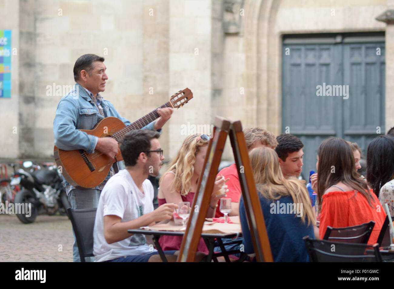 Musician playing guitar to restaurant diners outdoors in Bordeaux Stock ...