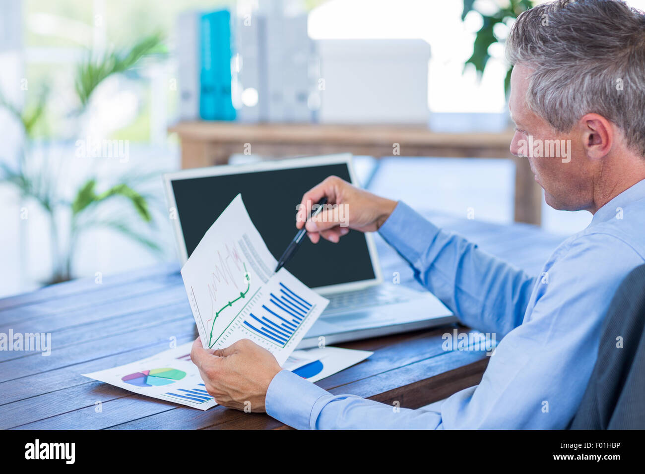 Businessman looking at documents with graphic Stock Photo - Alamy