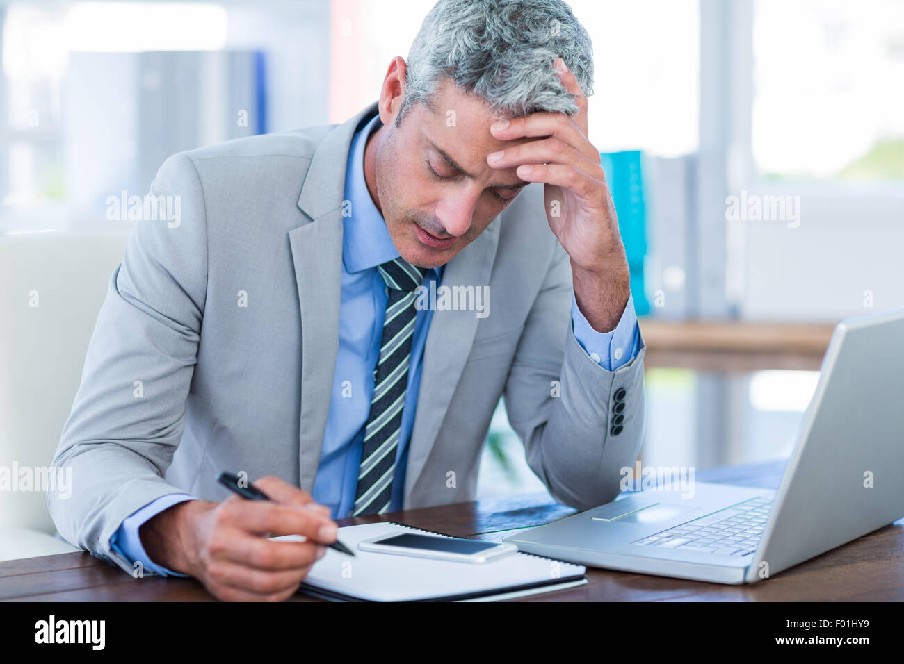 Irritated businessman trying to work Stock Photo - Alamy