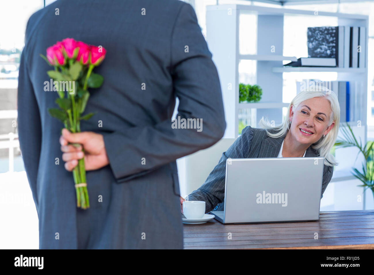 Businessman hiding flowers behind back for colleague Stock Photo - Alamy