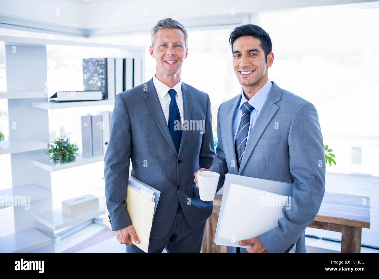 Happy businessman looking at camera and holding files Stock Photo - Alamy