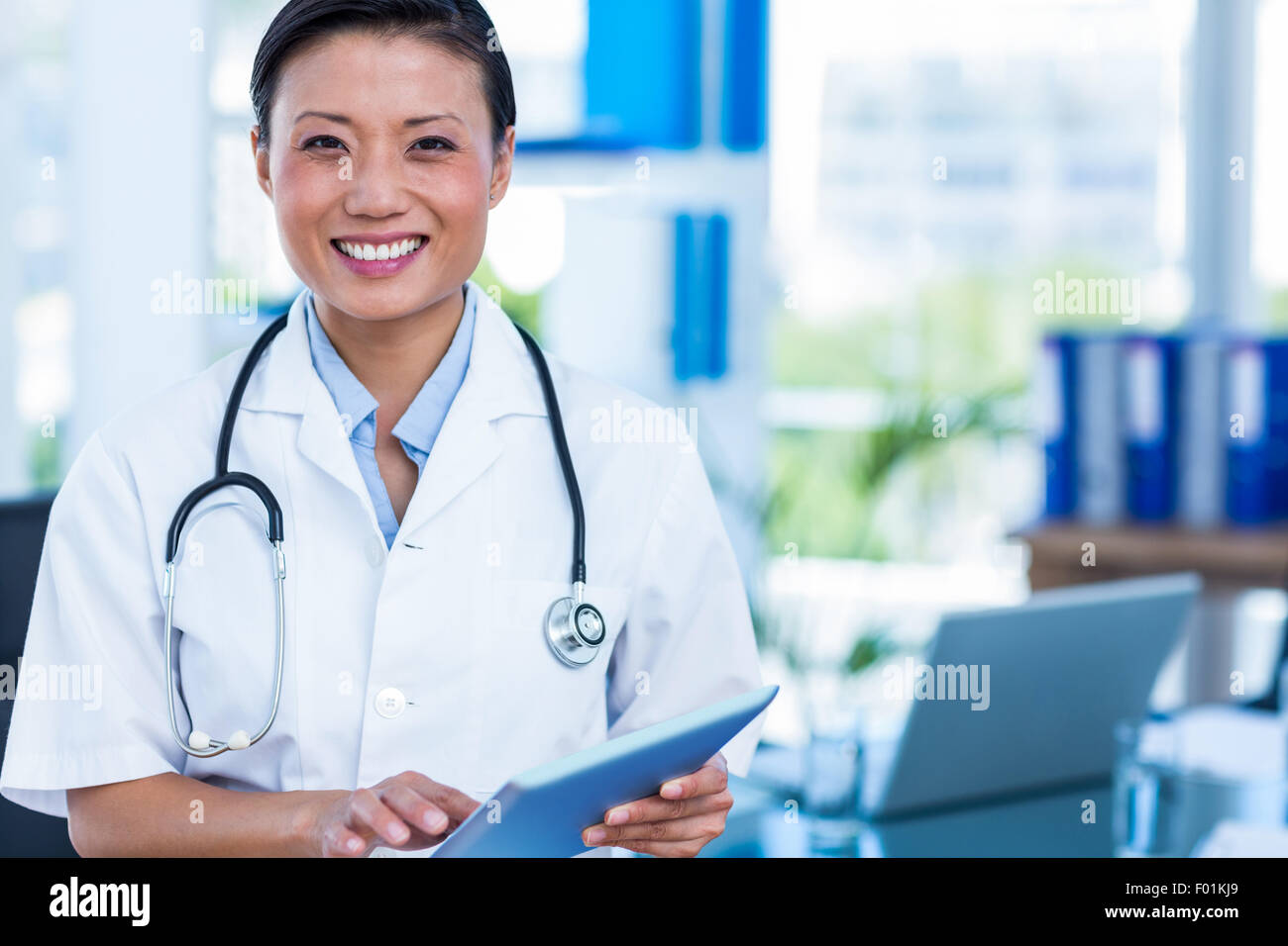 Happy doctor smiling at camera holding tablet Stock Photo - Alamy