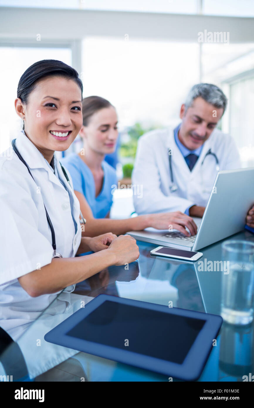Happy doctor looking at camera while colleagues are talking Stock Photo ...