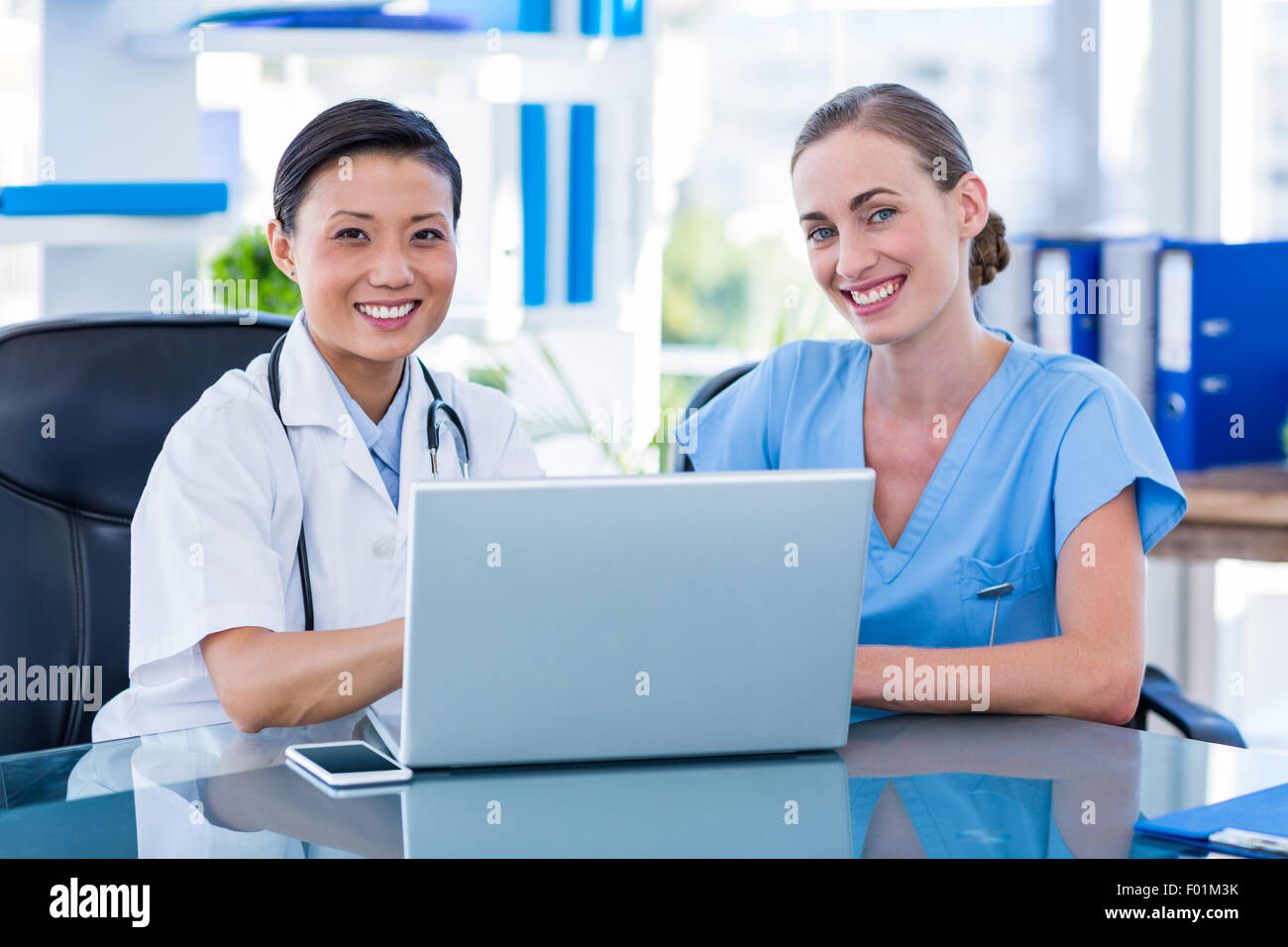 Doctor and nurse looking at laptop and smiling at camera Stock Photo ...