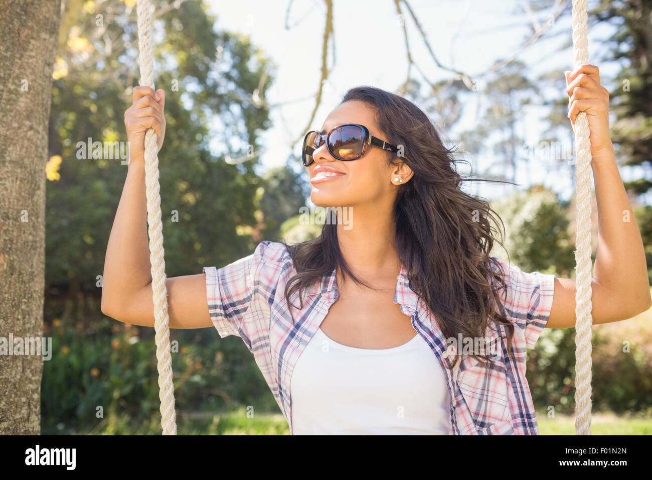 Pretty brunette swinging in park Stock Photo - Alamy