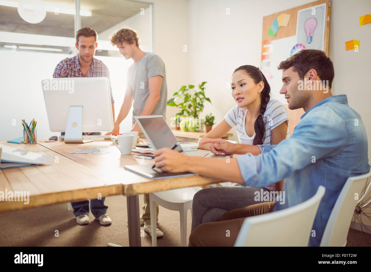 Creative business team gathered around laptops Stock Photo - Alamy