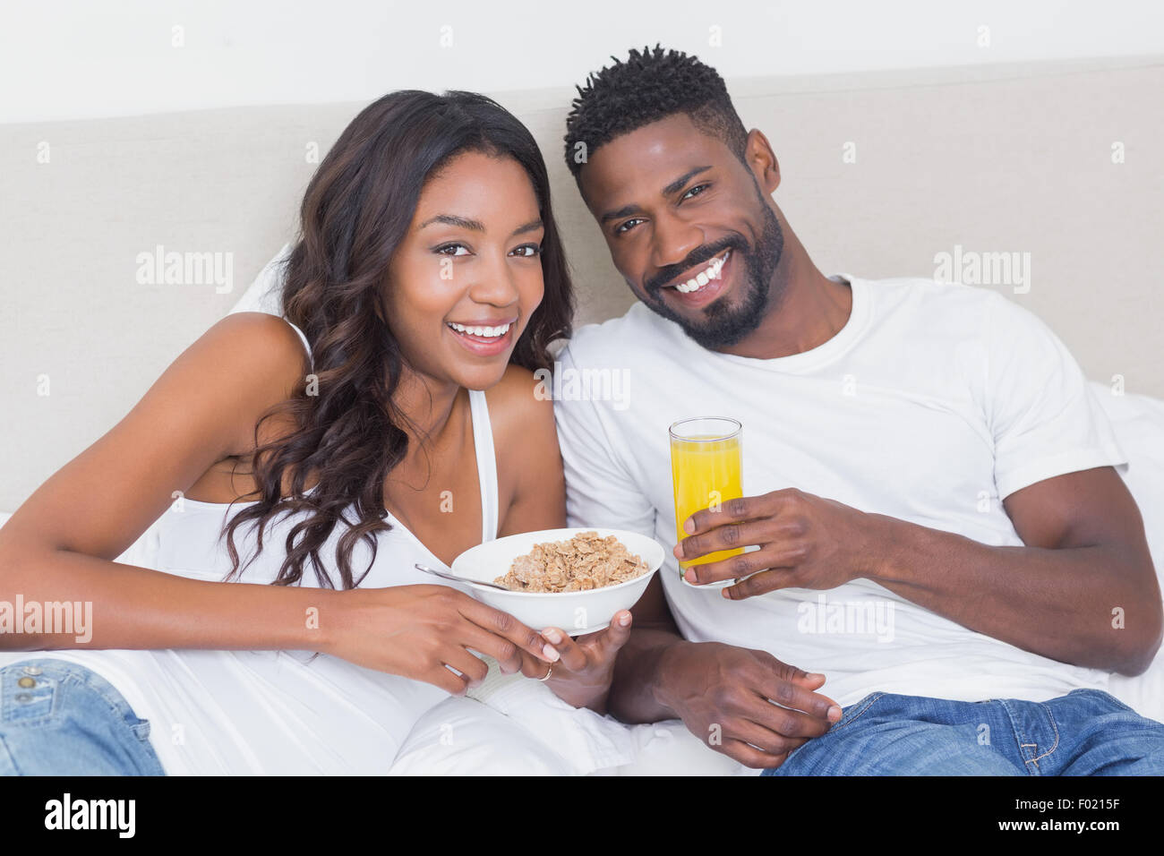 Relaxed couple in bed together eating cereal Stock Photo - Alamy