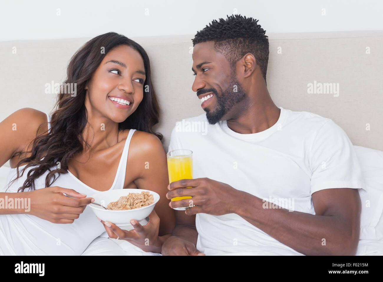 Relaxed couple in bed together eating cereal Stock Photo - Alamy