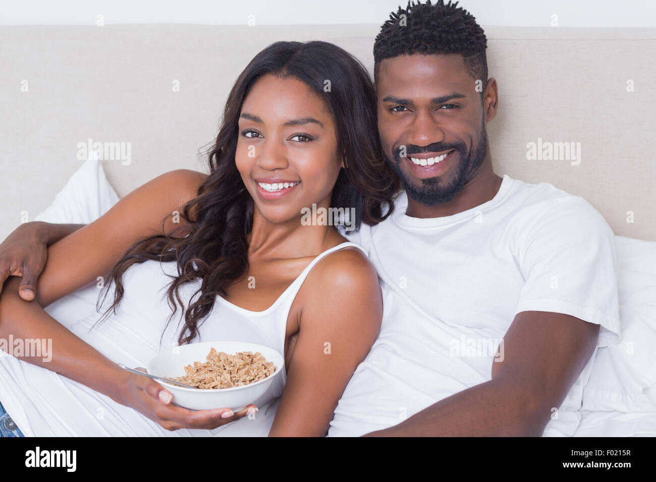 Relaxed couple in bed together eating cereal Stock Photo - Alamy