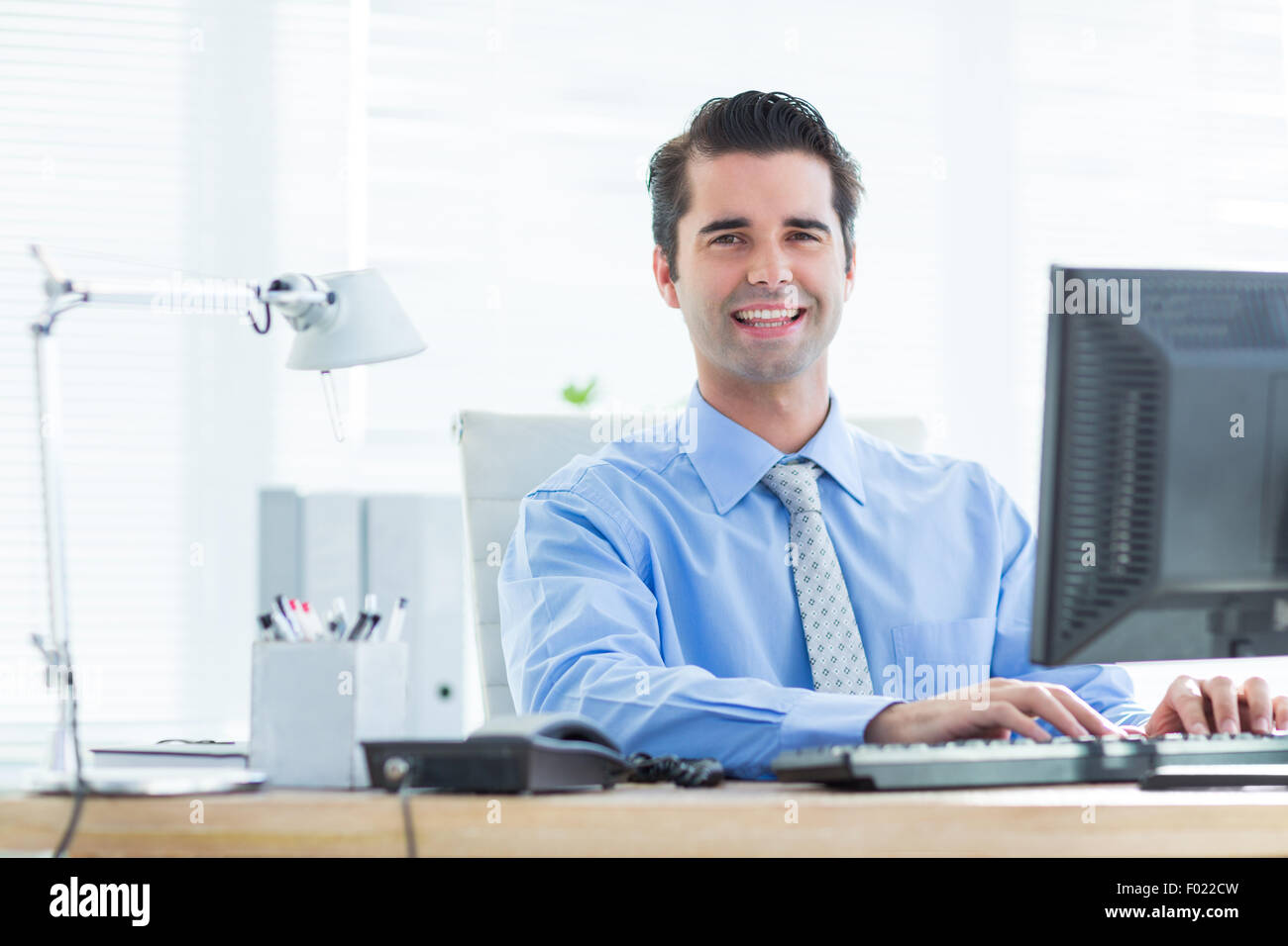 Smiling businessman using his computer Stock Photo - Alamy