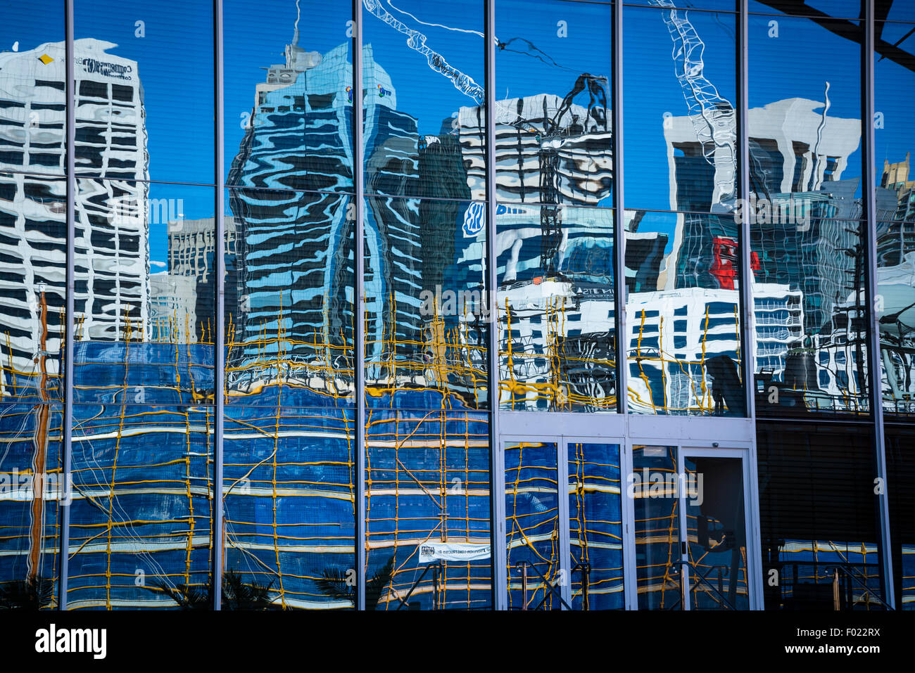 Distorted reflections of buildings, cranes and scaffolding a glass ...