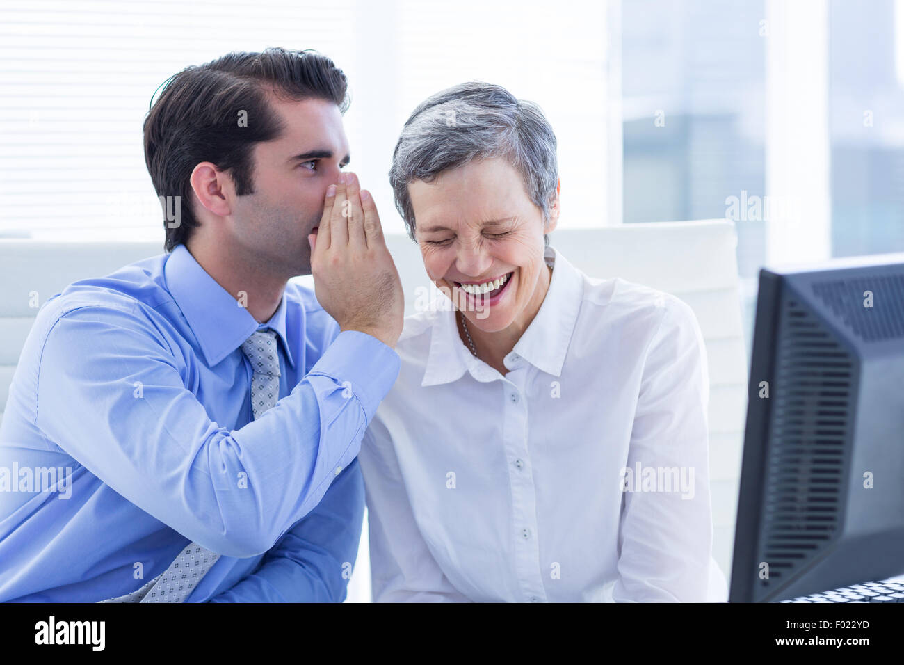Two business people looking at a paper while working on computer Stock ...