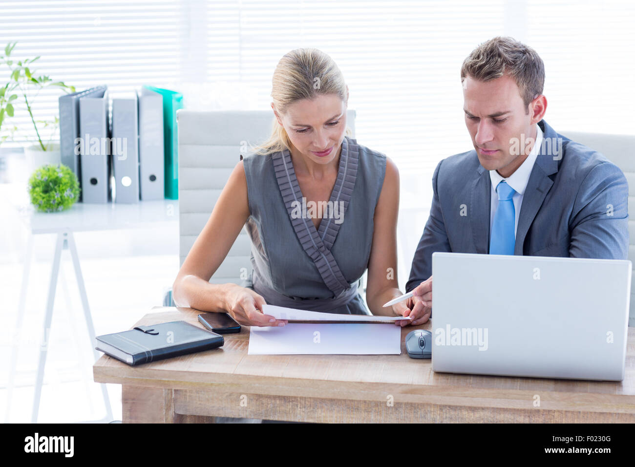 Serious colleagues working on folder Stock Photo - Alamy