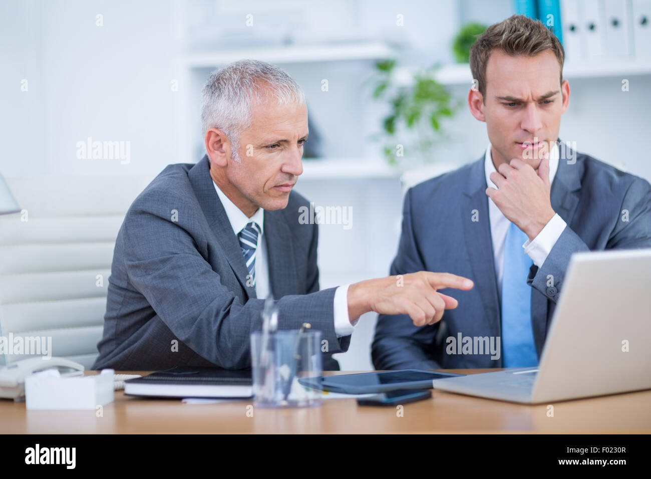 Serious businessmen working together on laptop Stock Photo - Alamy