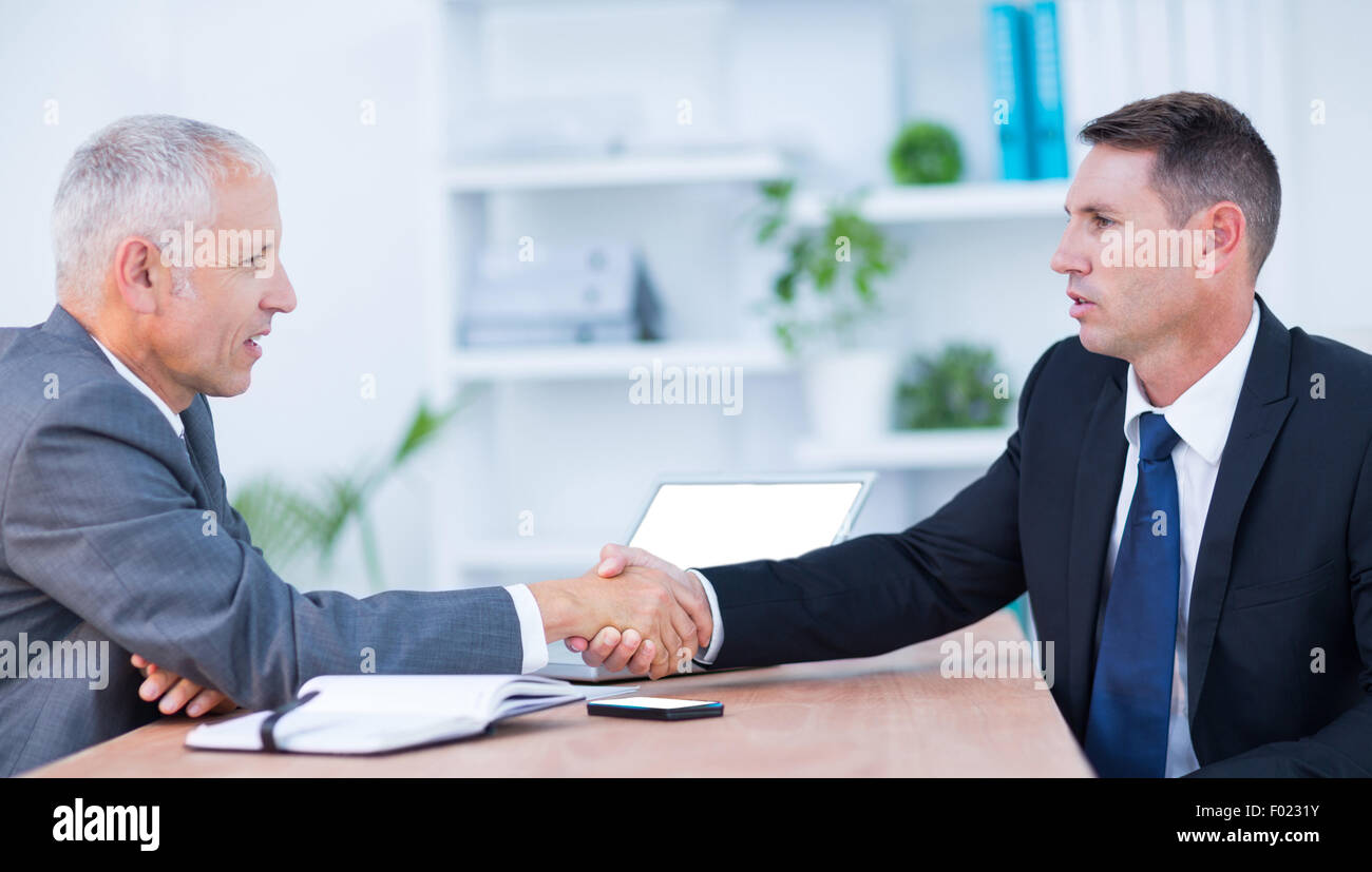 Two businessmen shaking hands and working Stock Photo - Alamy