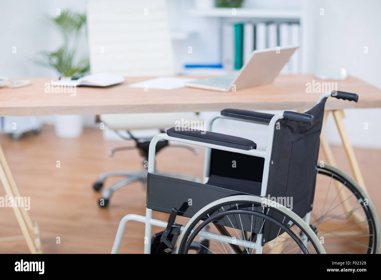 A free wheelchair at his desk Stock Photo - Alamy