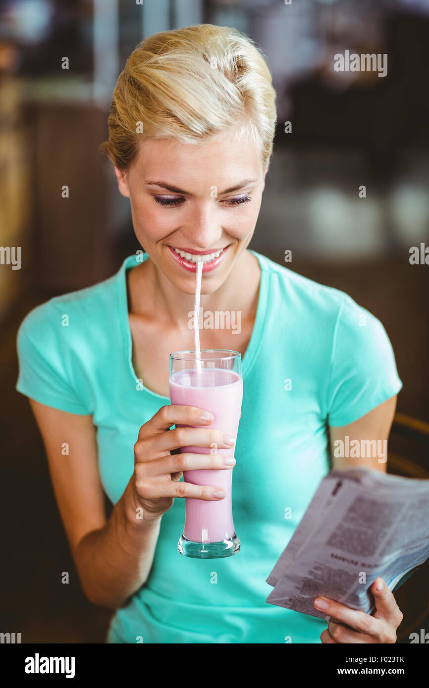 Smiling blonde woman enjoying her milkshake Stock Photo - Alamy