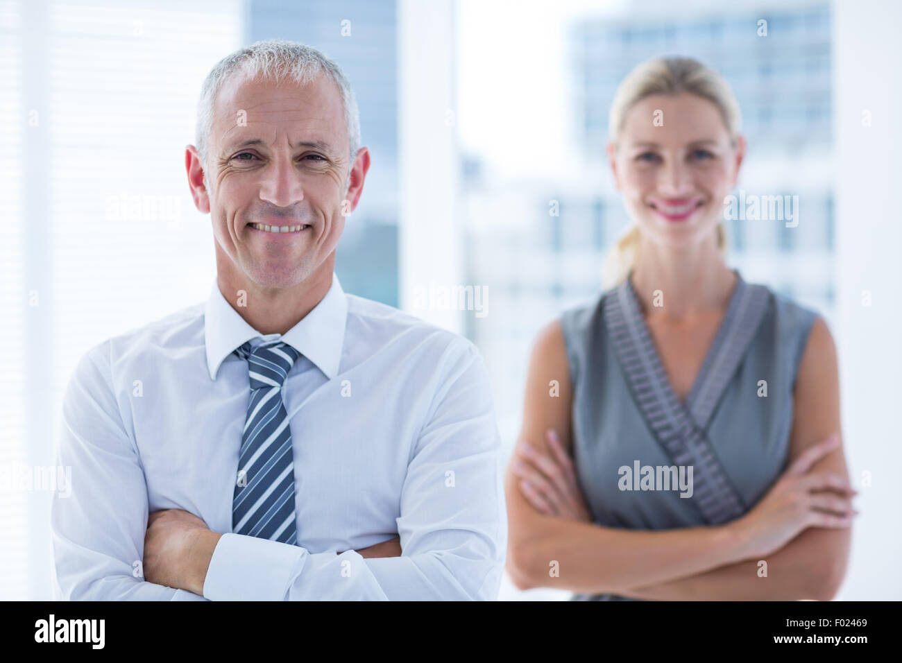 Two business people smiling at the camera in the office Stock Photo - Alamy